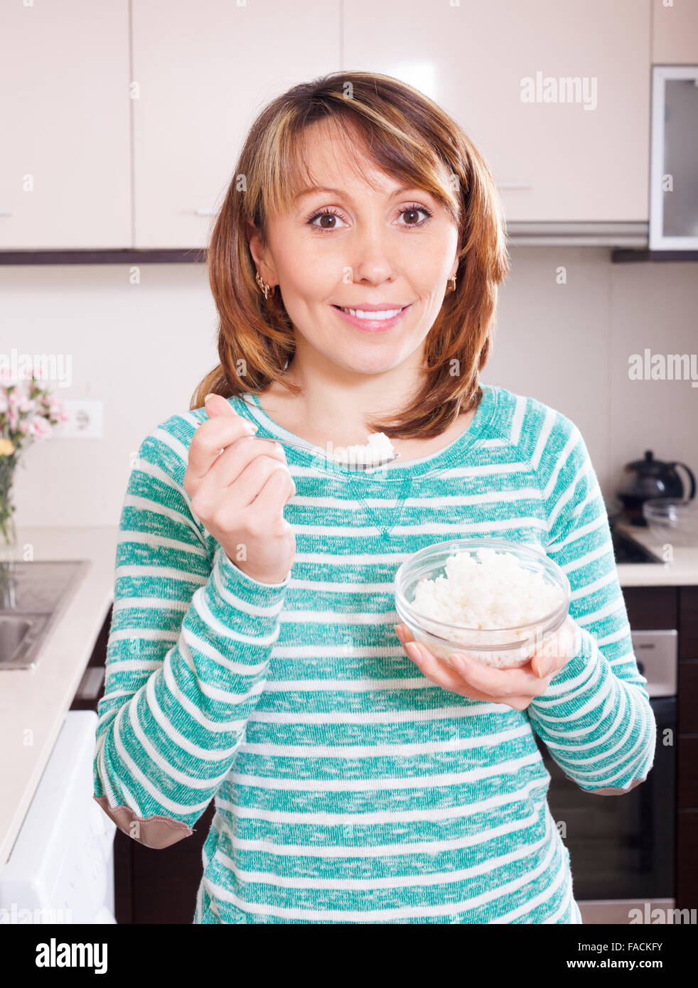 woman in green eating rice in kitchen Stock Photo - Alamy