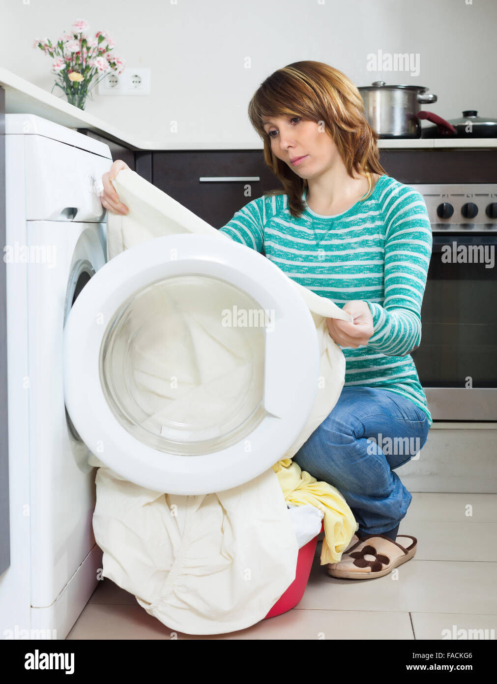 Home laundry. Unhappy girl using washing machine at home Stock Photo ...