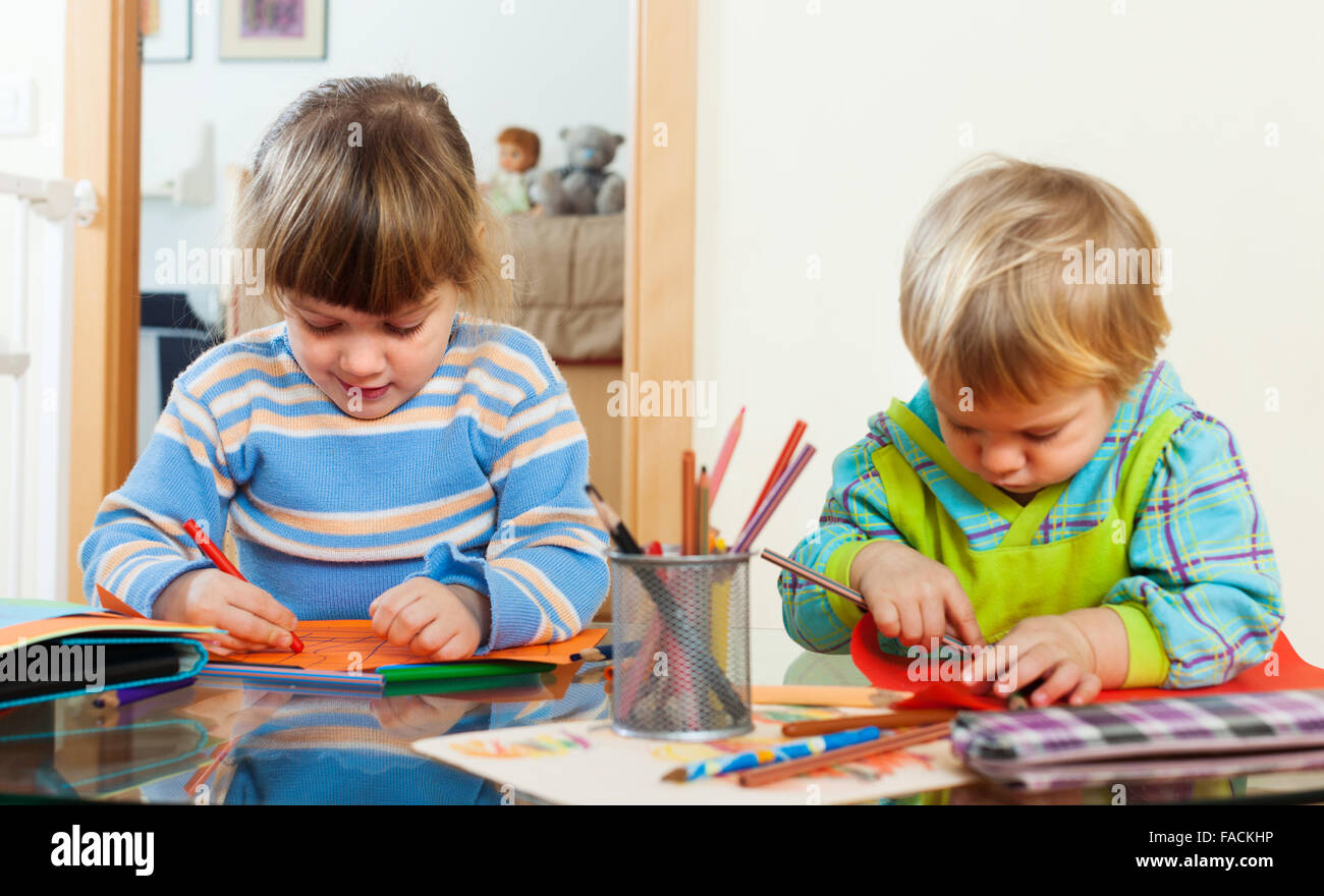 Two children playing with paper and pencils in home interior Stock ...