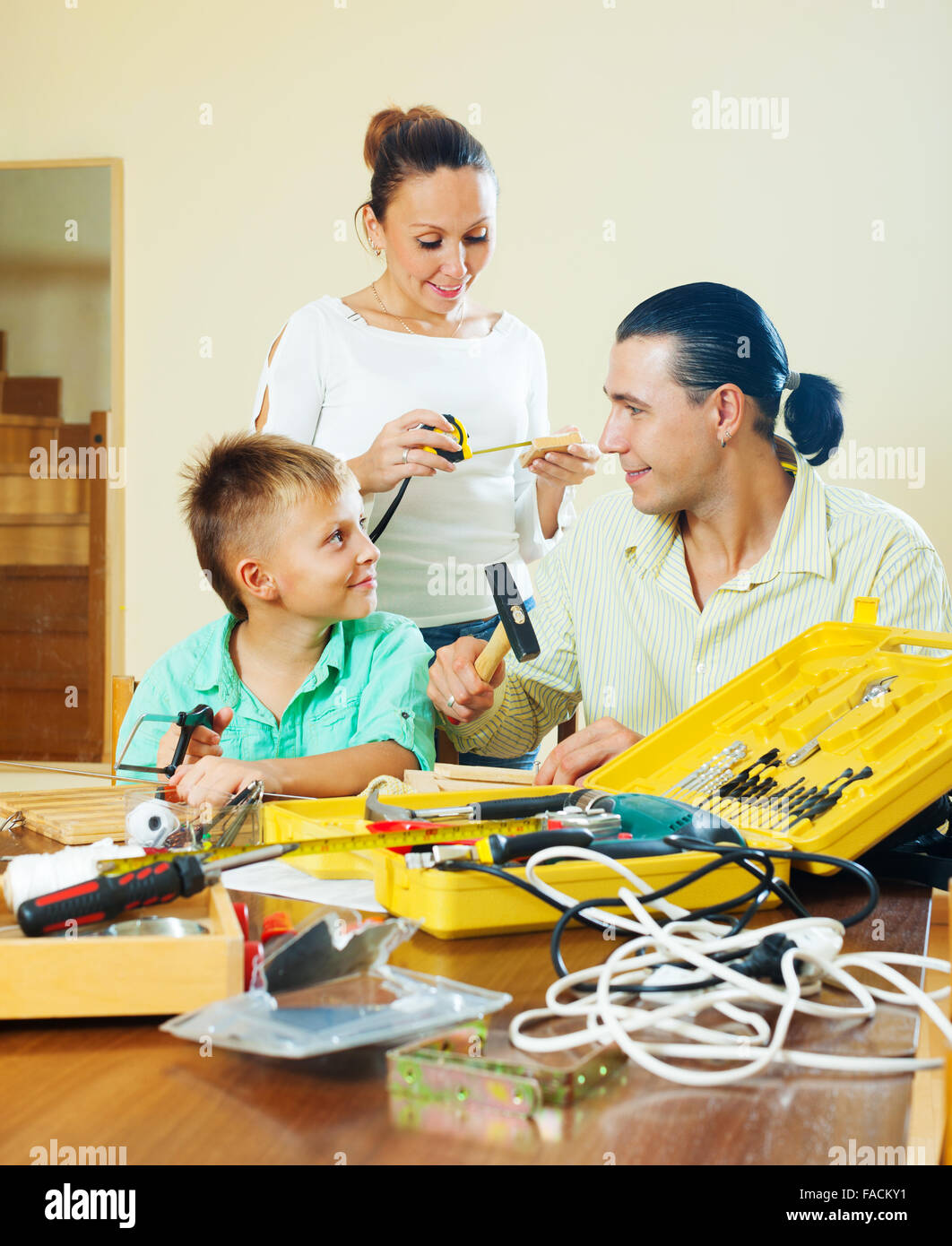 Happy family of three doing something with the working tools at home ...