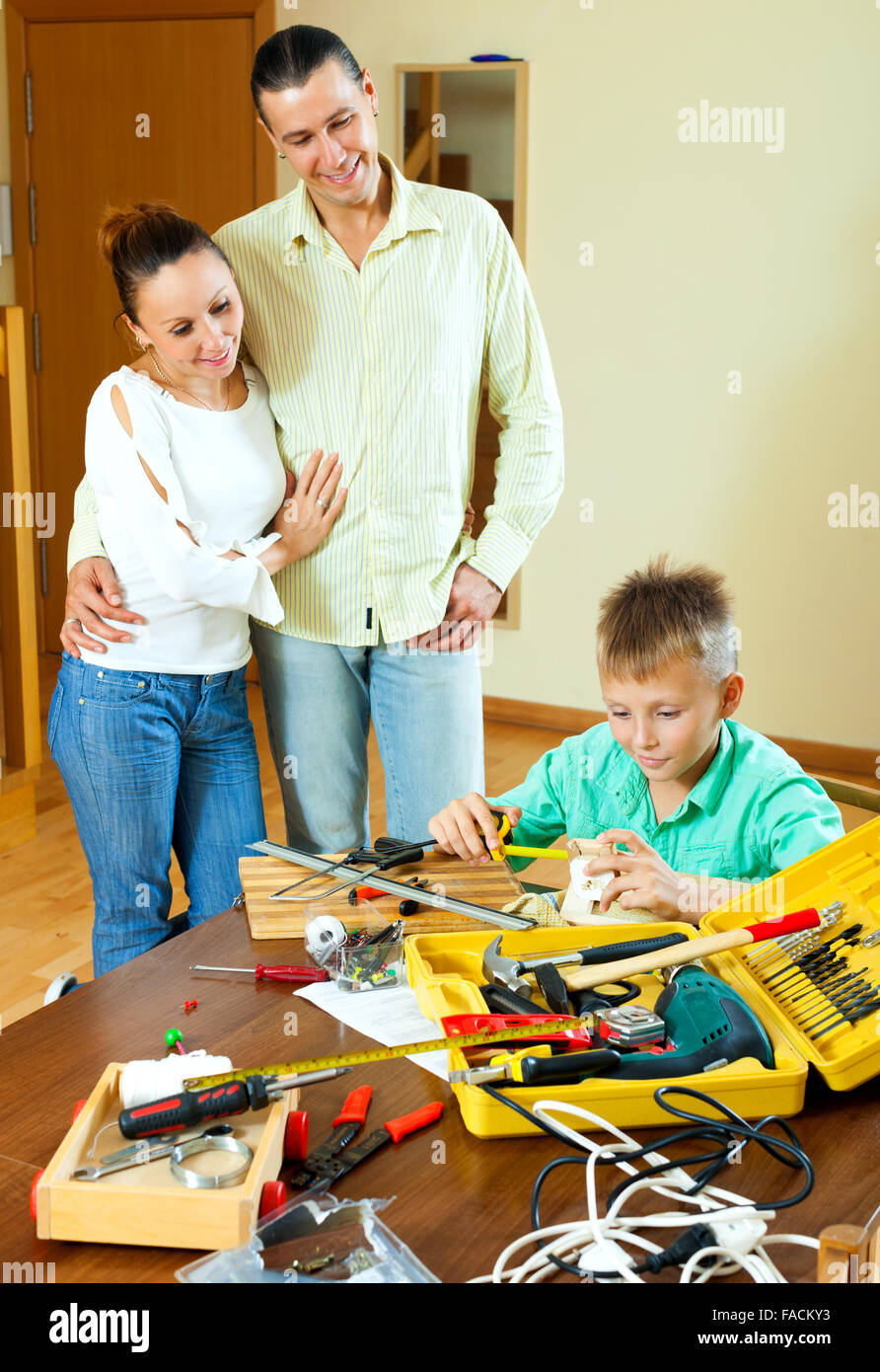 Happy teenager making something with working tools in living room at ...