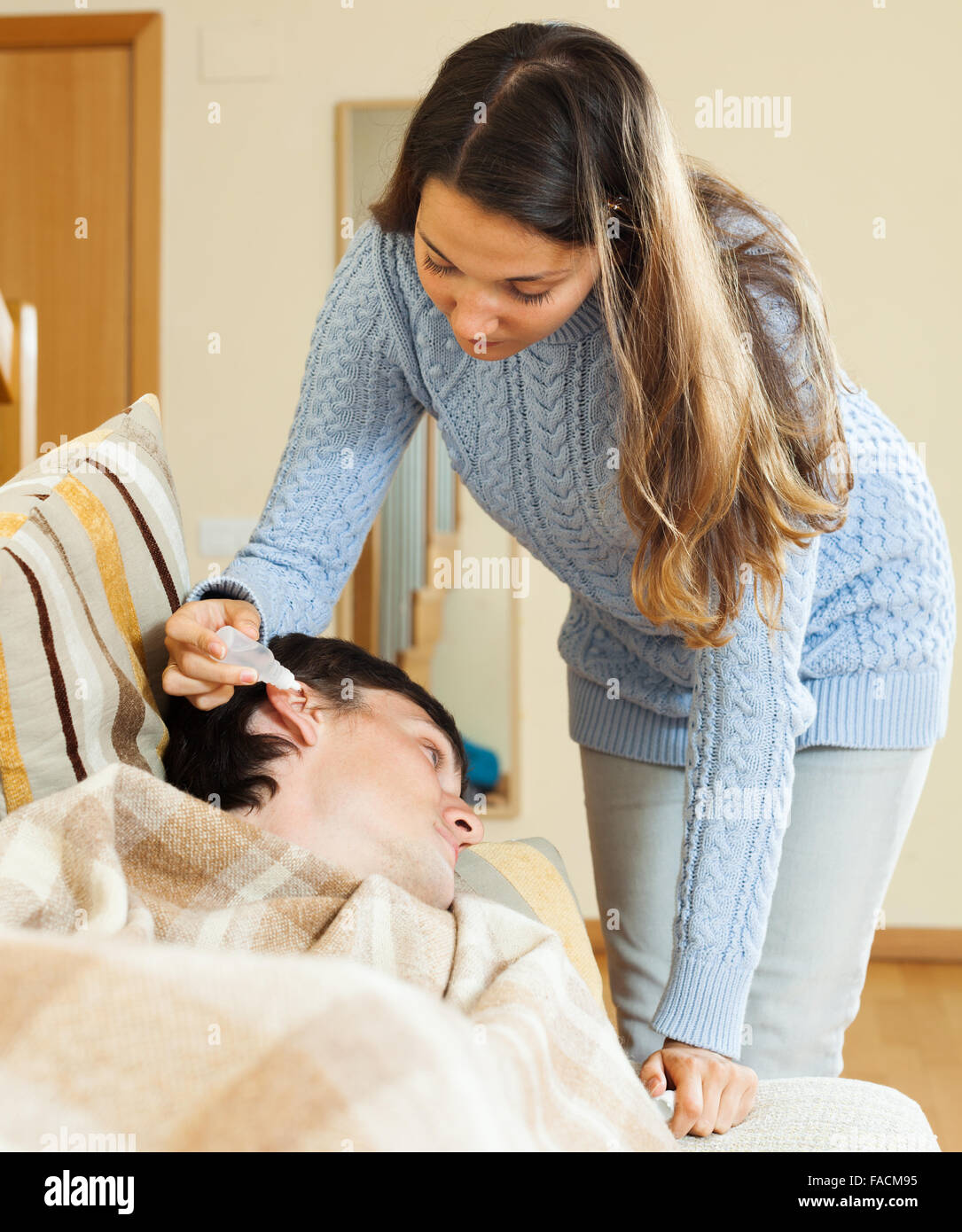 Girl dripping ear drops to man in living room Stock Photo - Alamy