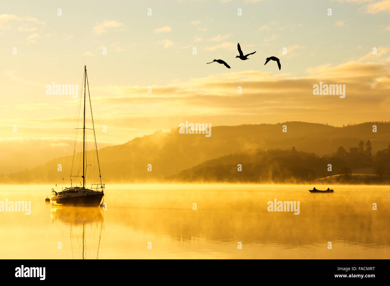 Sunrise over men fishing in a boat on Lake Windermere in Ambleside ...