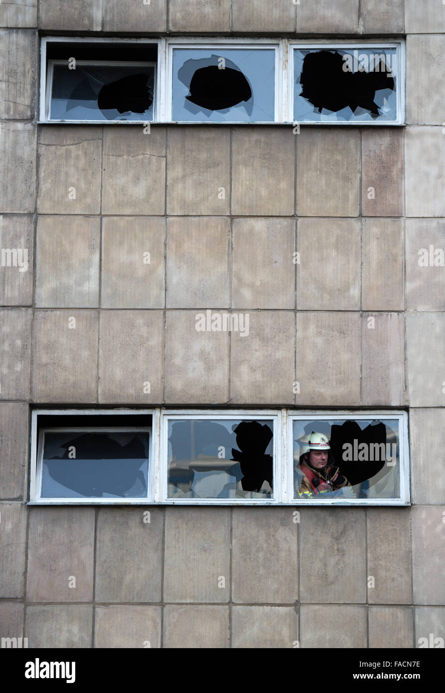 A firefighter stands behind a shattered window in an apartment block in ...