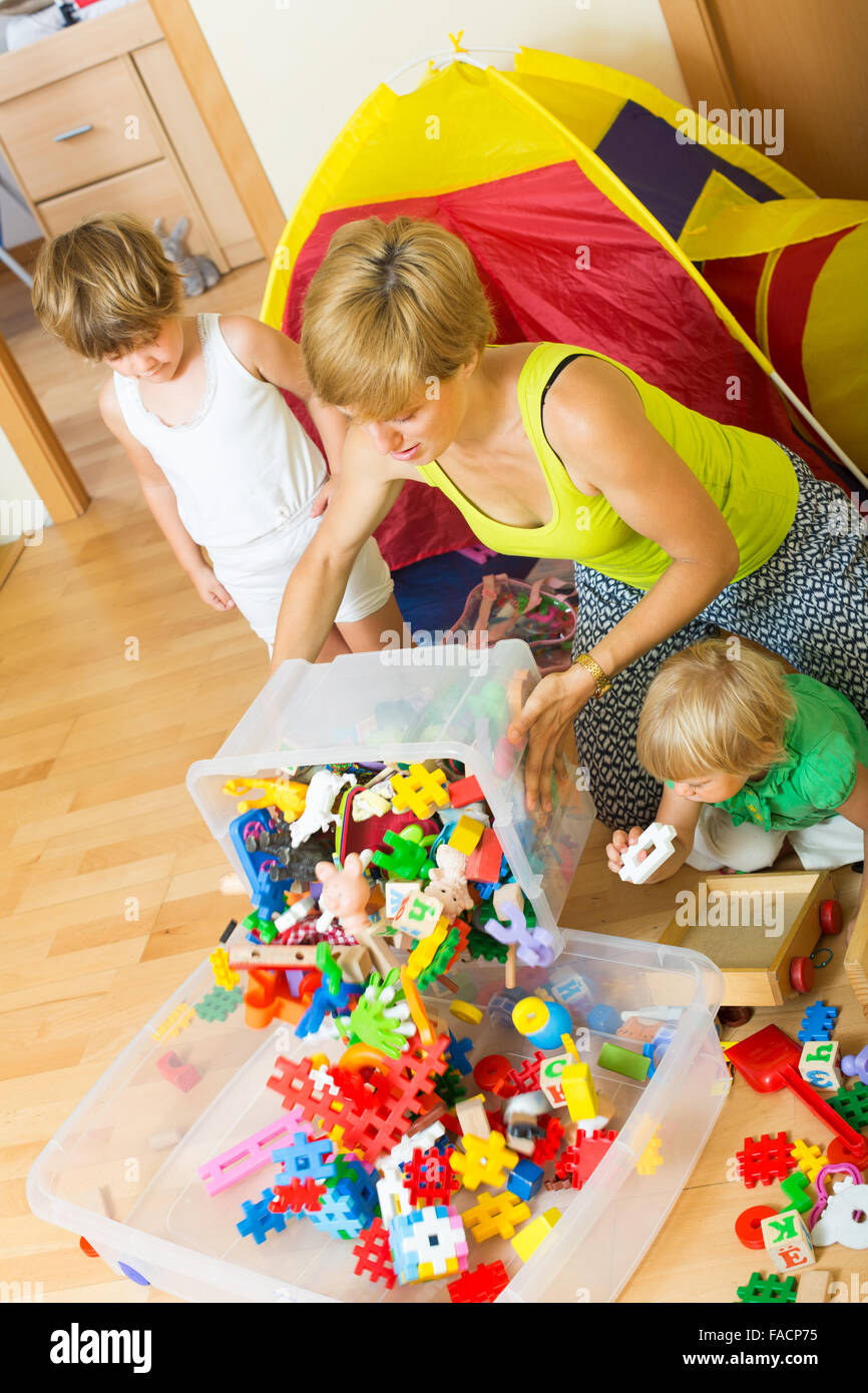 Two little children and mother collecting toys in plastic box Stock ...