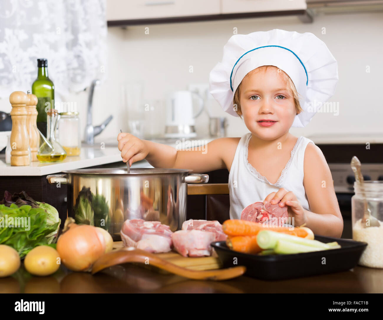 Little child in cook hat cooking soup in pan at kitchen Stock Photo - Alamy