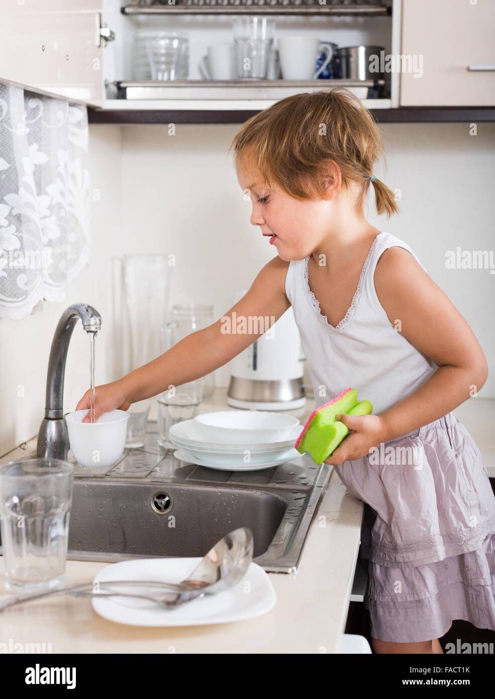 Small child cleaning dishes in the kitchen Stock Photo - Alamy