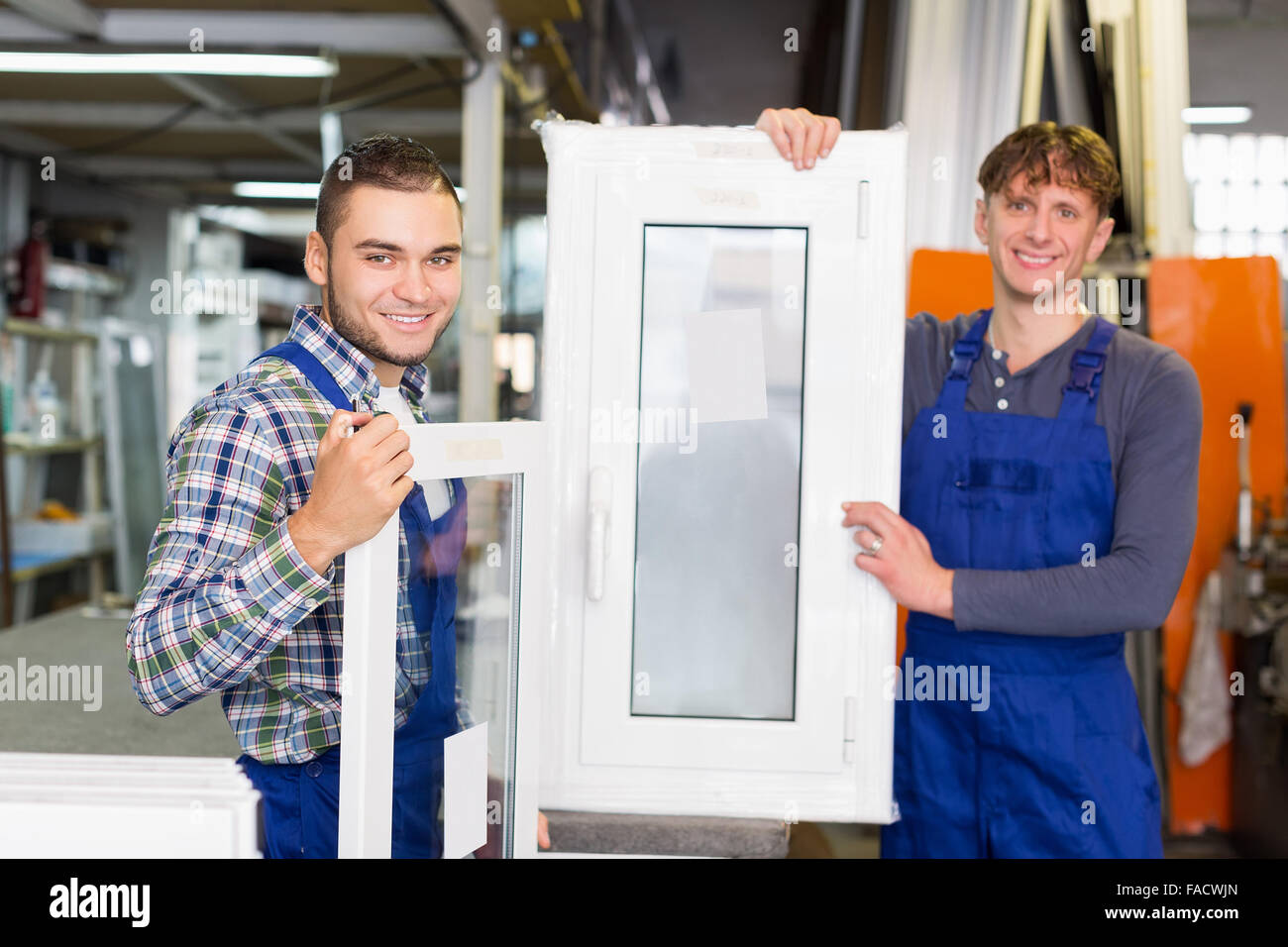 Positive workmen together checking windows production at modern factory ...