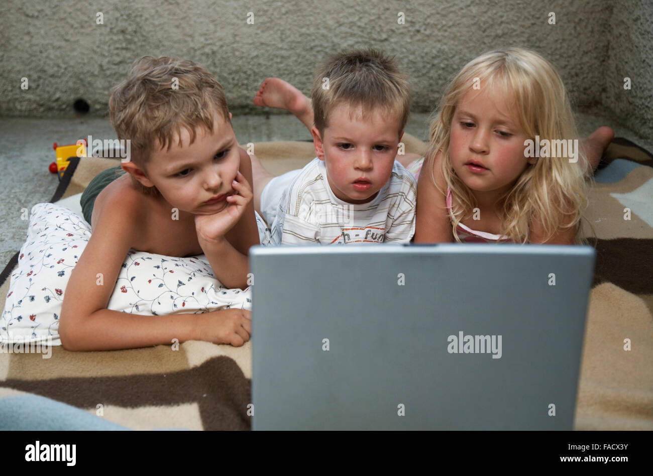 Three children and are looking into the computer Stock Photo - Alamy