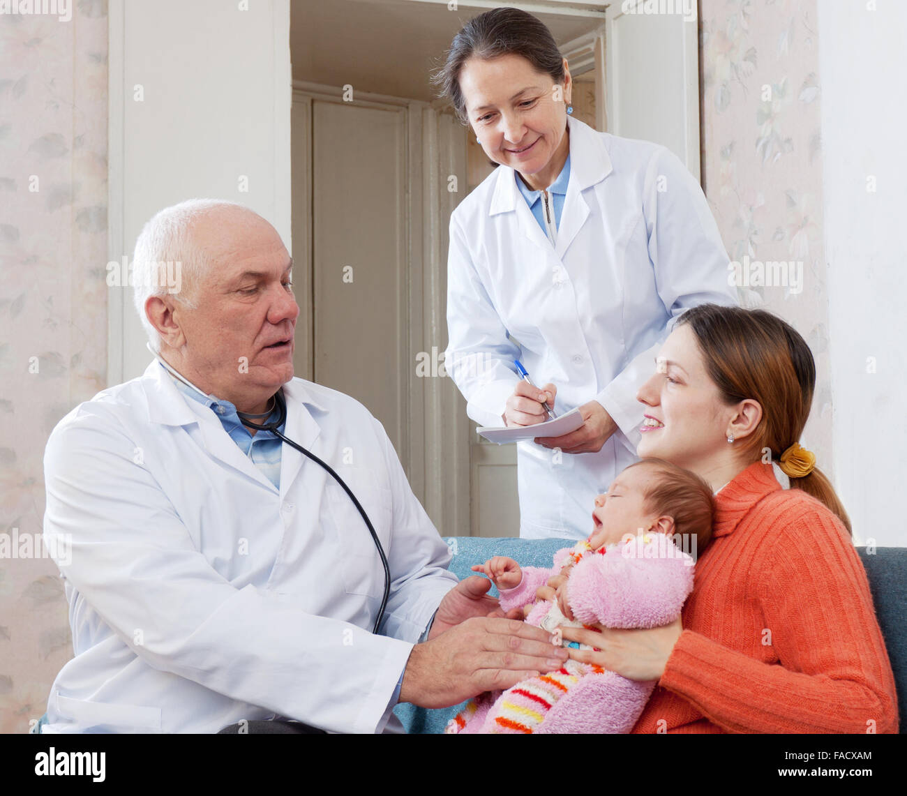 pediatrician doctor examining little baby in the arms of mother Stock ...