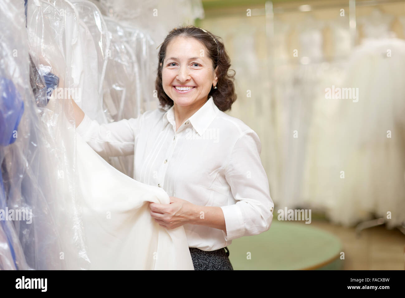 Shop assistant with bridal dress at wedding store Stock Photo - Alamy