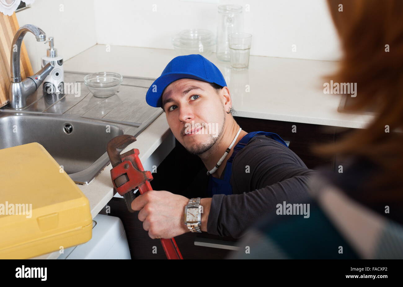 Plumber repairing a kitchen sink for housewife Stock Photo - Alamy