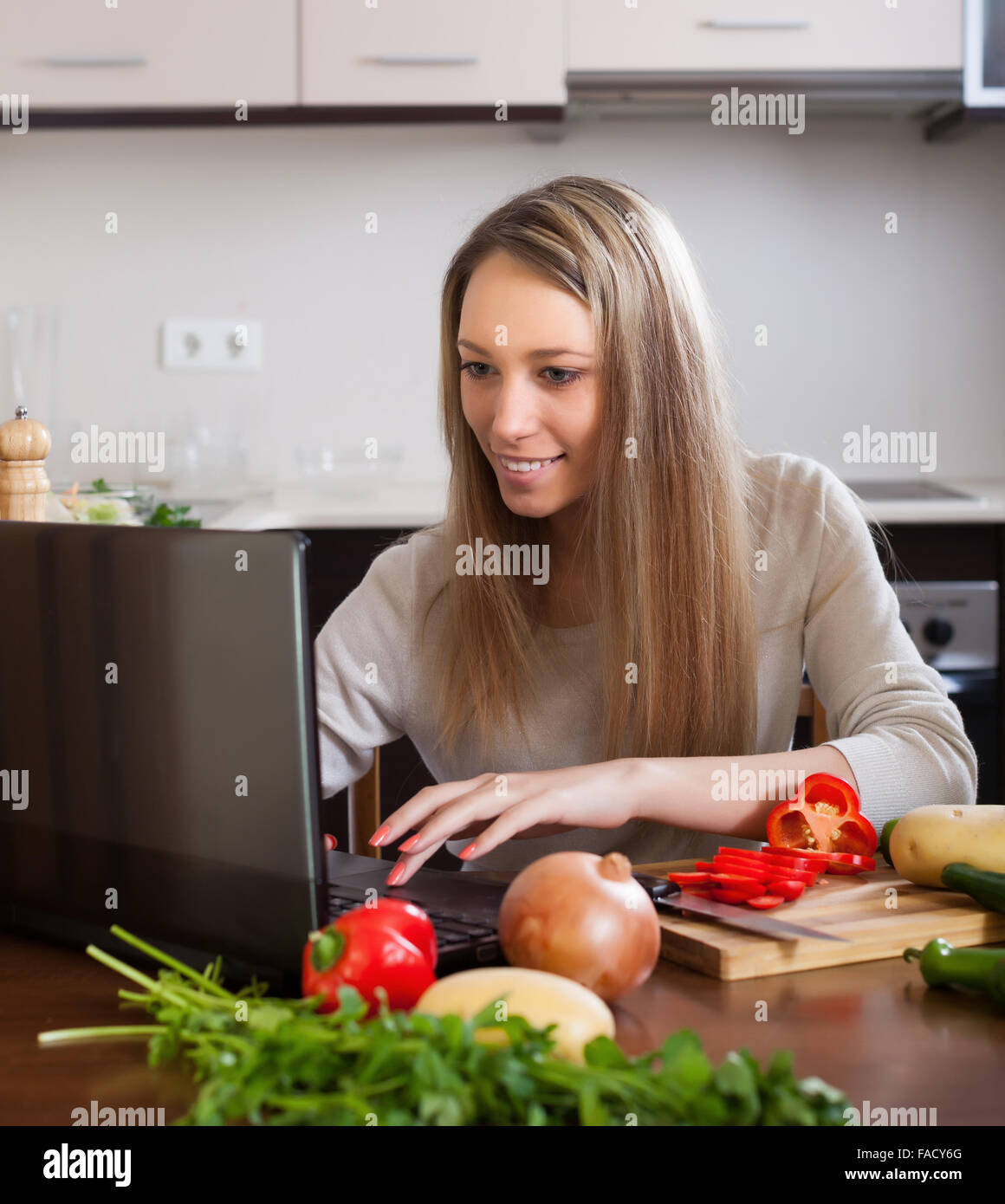 Casual woman using notebook while cooking lunch Stock Photo - Alamy