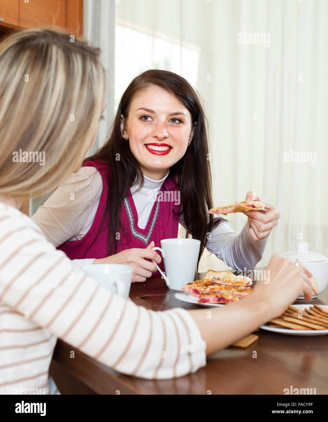 two women sitting at table, gossiping and drinking tea in home Stock ...