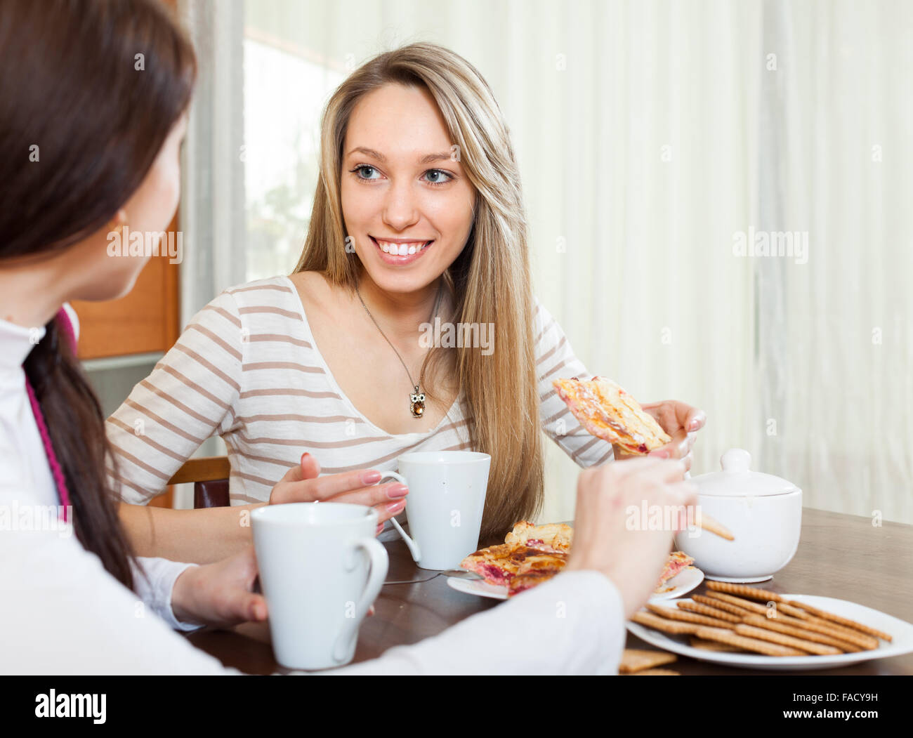 happy girls drinking tea and gossiping in home Stock Photo - Alamy