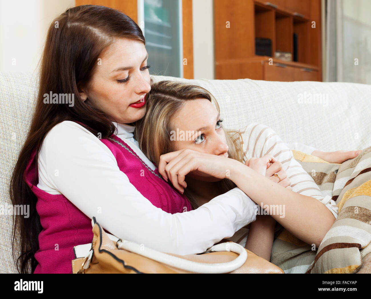 Young woman consoling the crying girl at sofa in home Stock Photo - Alamy