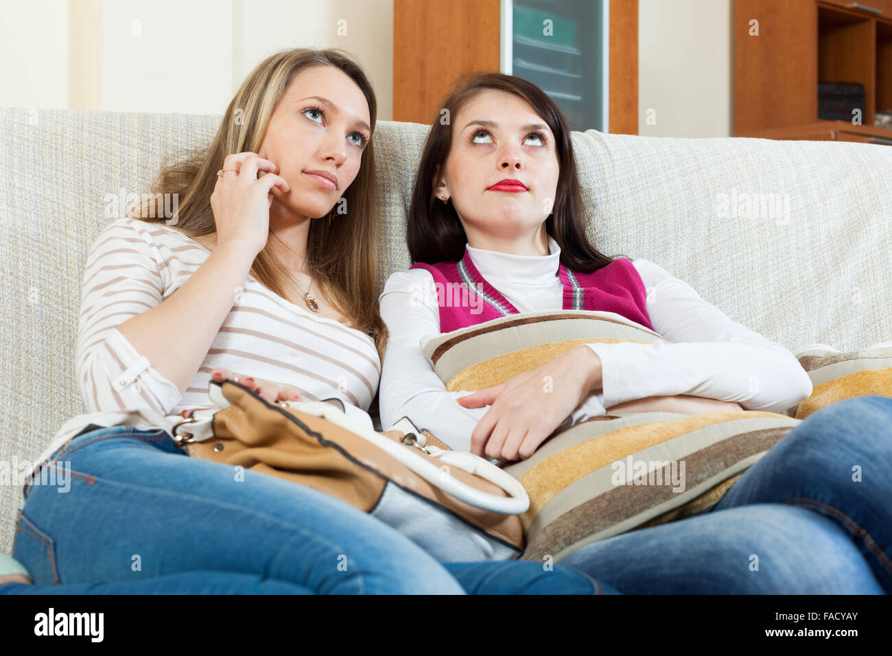 Two sadness women together on sofa Stock Photo - Alamy