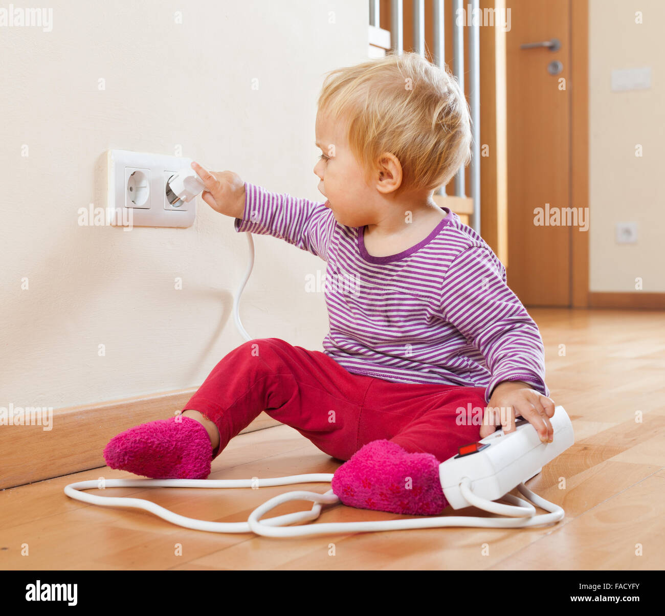 Toddler playing with extension cord and electric outlet at home Stock ...
