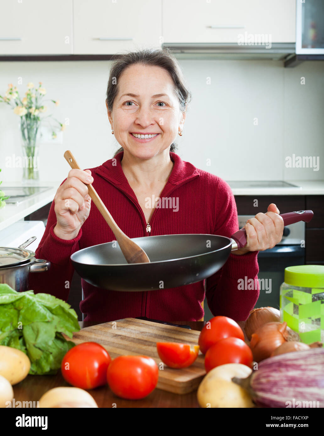 Smiling mature woman cooking with skillet in domestic kitchen Stock ...
