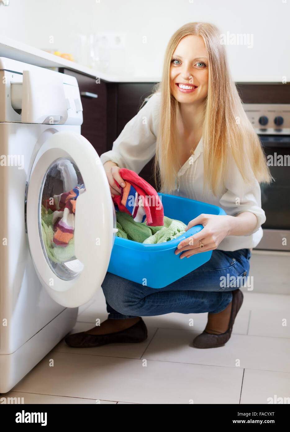 Home laundry. Happy woman loading the washing machine Stock Photo - Alamy