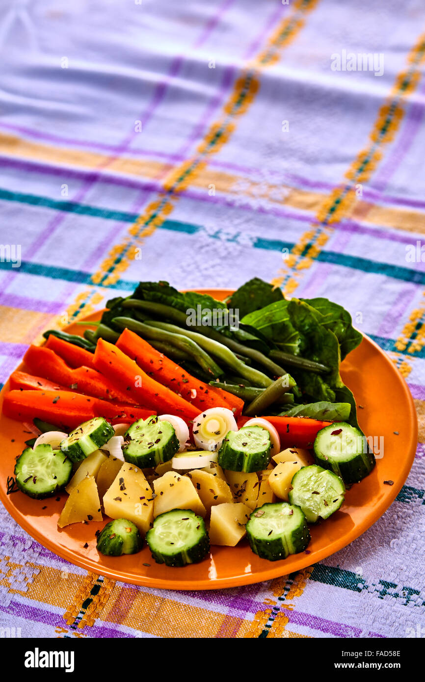 Ladle of steamed freshly harvested young vegetables including crinkle ...