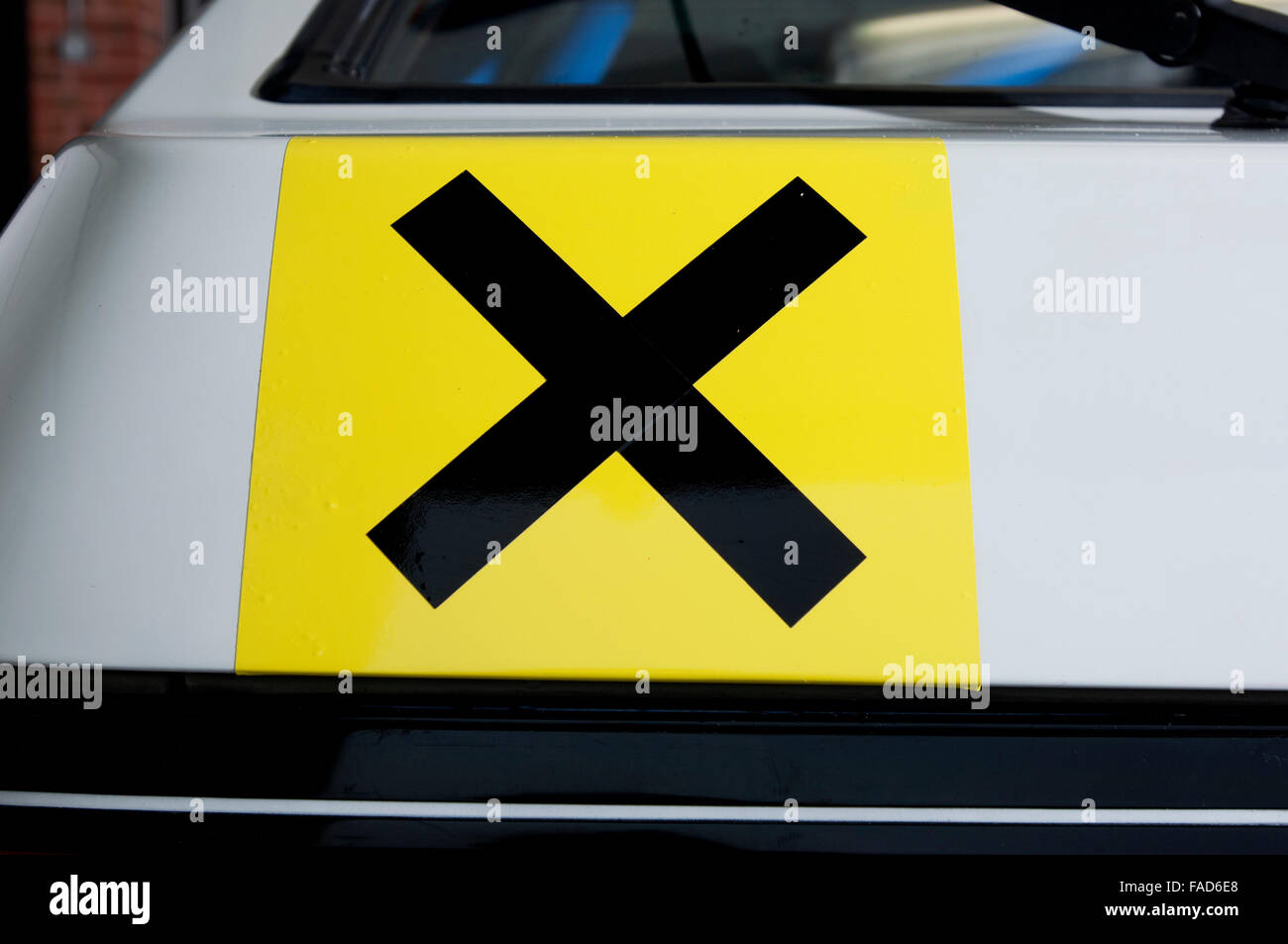 Novice sticker on a car at a race track, black X on yellow square warns ...