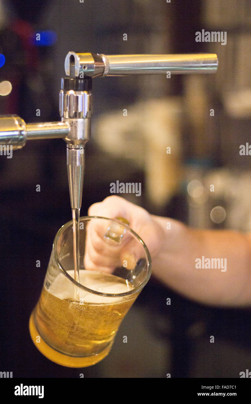 Lager draft beer pump and barman pulling pint of beer into glass in ...