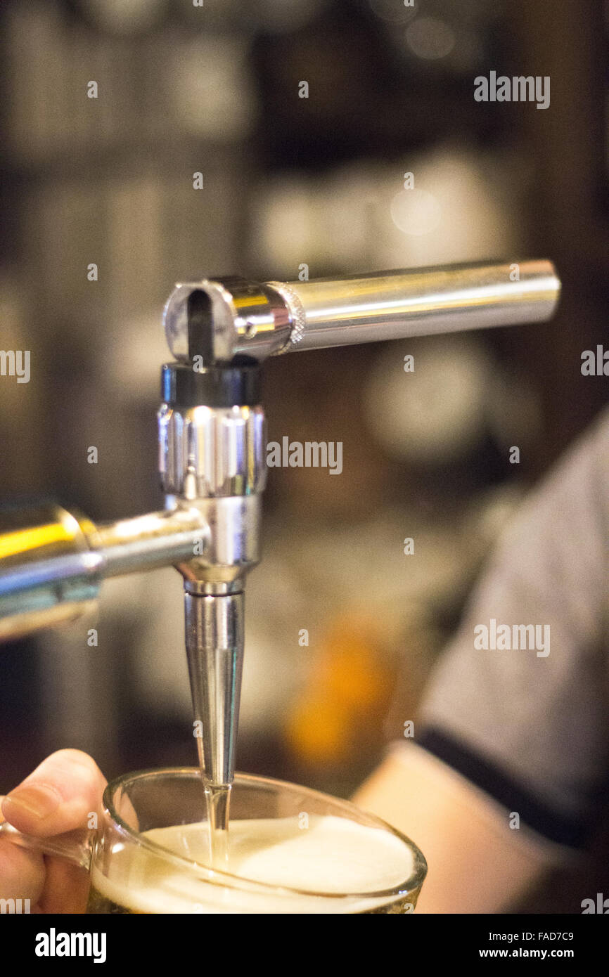 Lager draft beer pump and barman pulling pint of beer into glass in ...