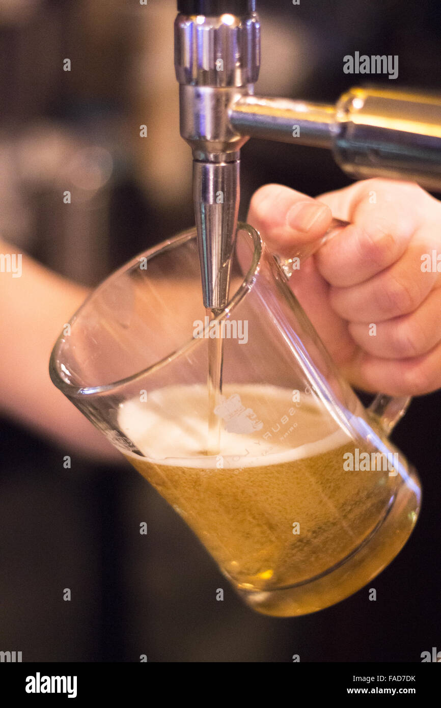 Lager draft beer pump and barman pulling pint of beer into glass in ...