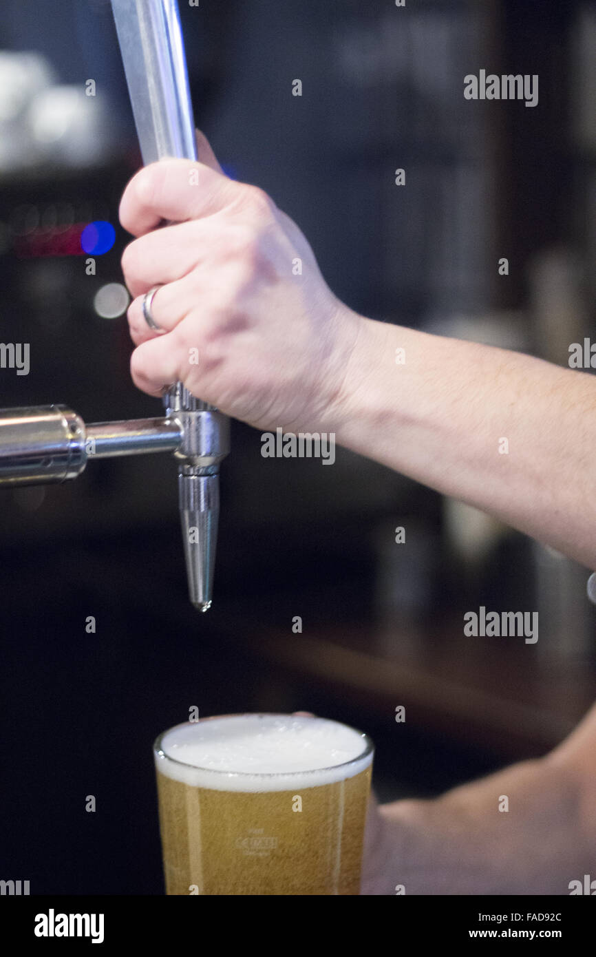 Lager draft beer pump and barman pulling pint of beer into glass in ...