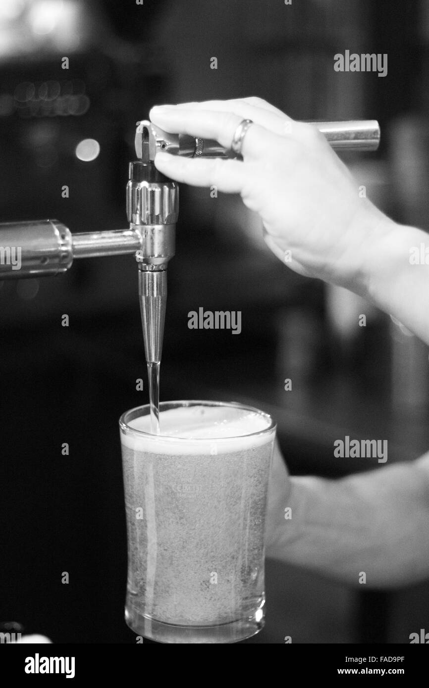 Lager draft beer pump and barman pulling pint of beer into glass in ...