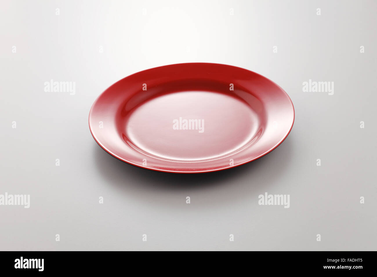 Empty red plate on the white background Stock Photo - Alamy
