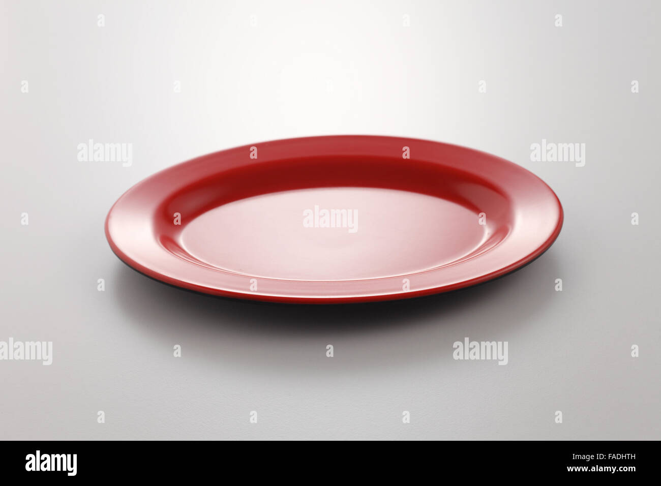 Empty red plate on the white background Stock Photo - Alamy
