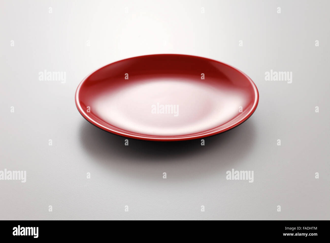 Empty red plate on the white background Stock Photo - Alamy