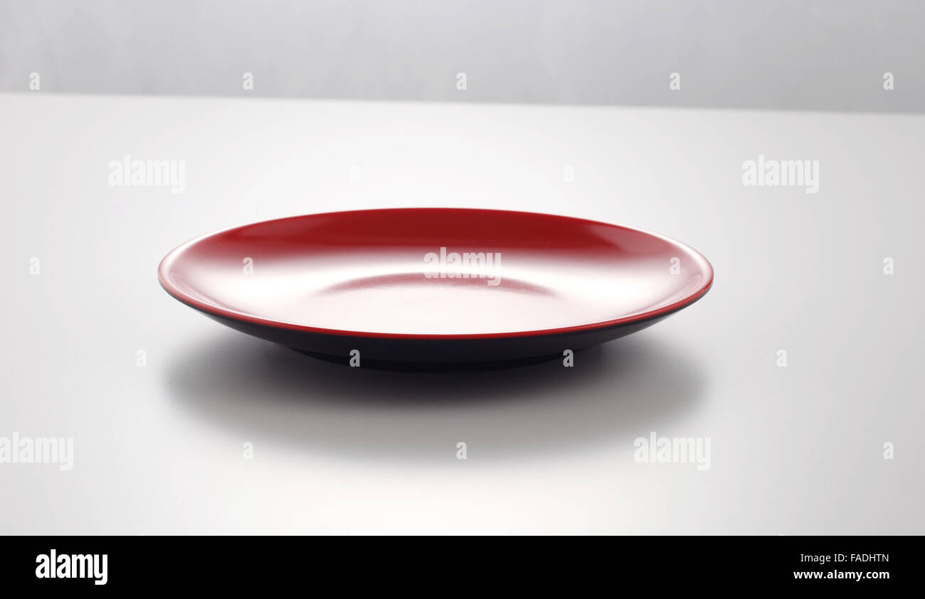 Empty red plate on the white background Stock Photo - Alamy