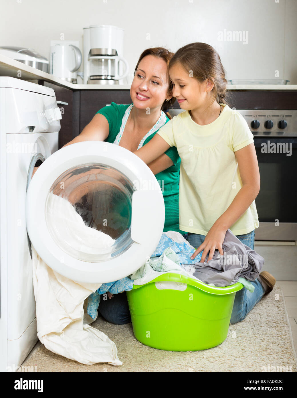 Home family laundry. Happy mother with preschooler daughter loading ...