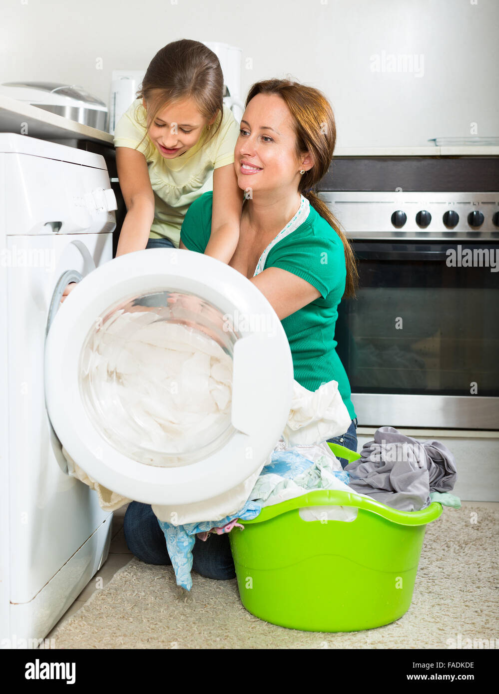 Home laundry. Positive smiling woman with playful daughter using ...