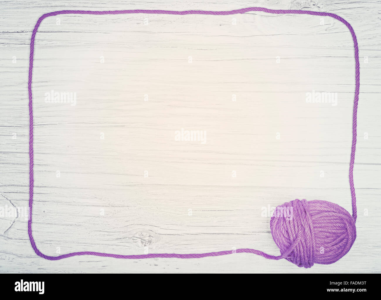 Violet frame made of yarn on wooden board, background with space for ...