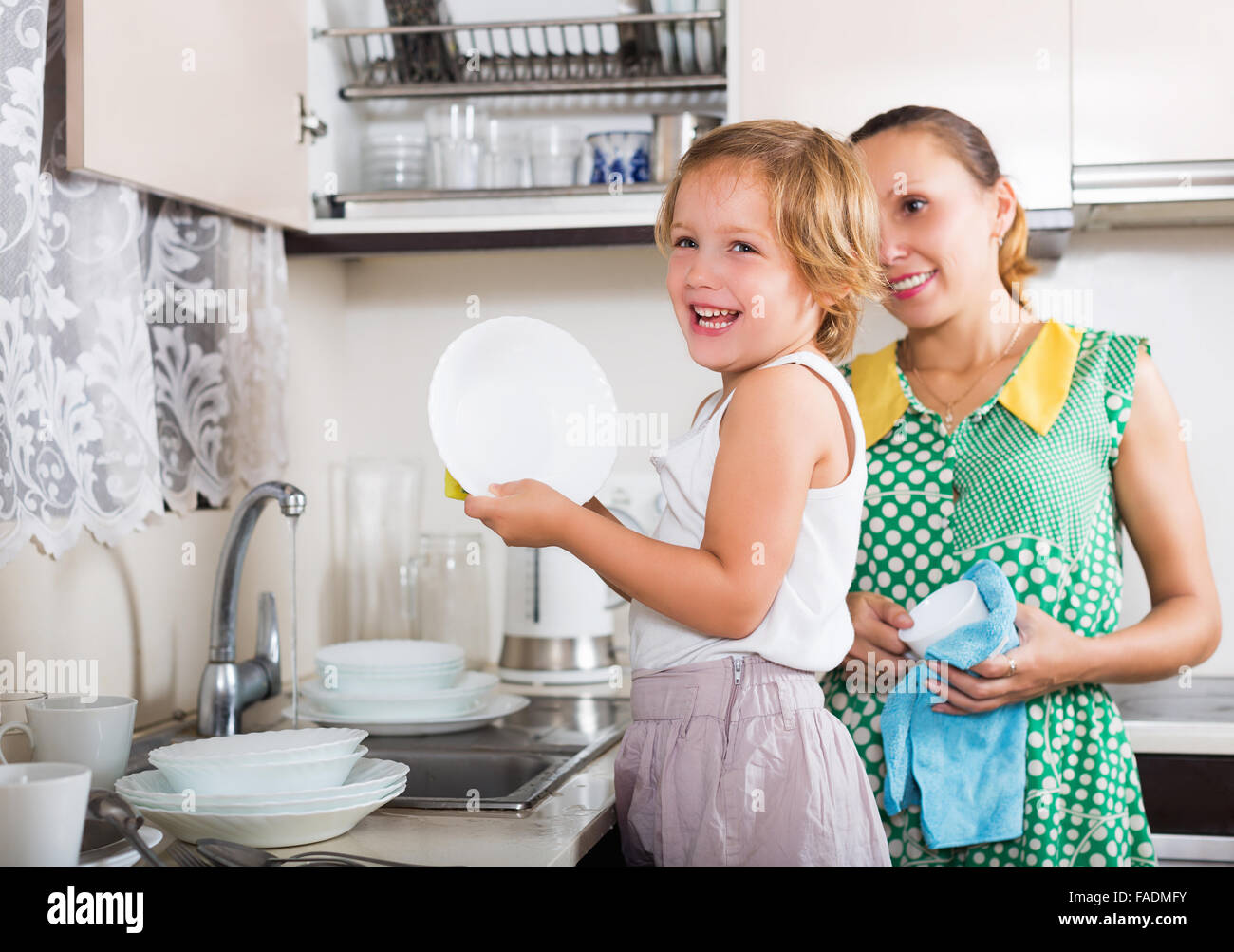 Happy daughter with mother washing plates in kitchen Stock Photo - Alamy