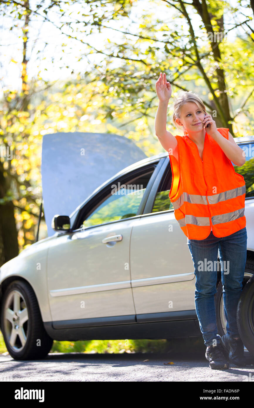 Young female driver wearing a high visibility vest, calling the ...