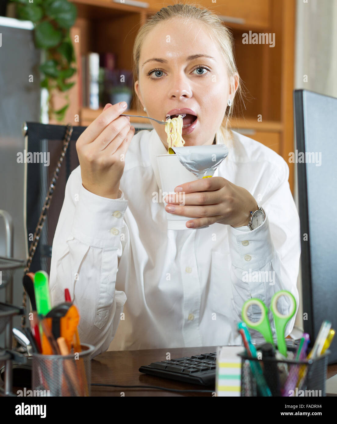 Hungry employee eating unhealthy noodles at office Stock Photo - Alamy