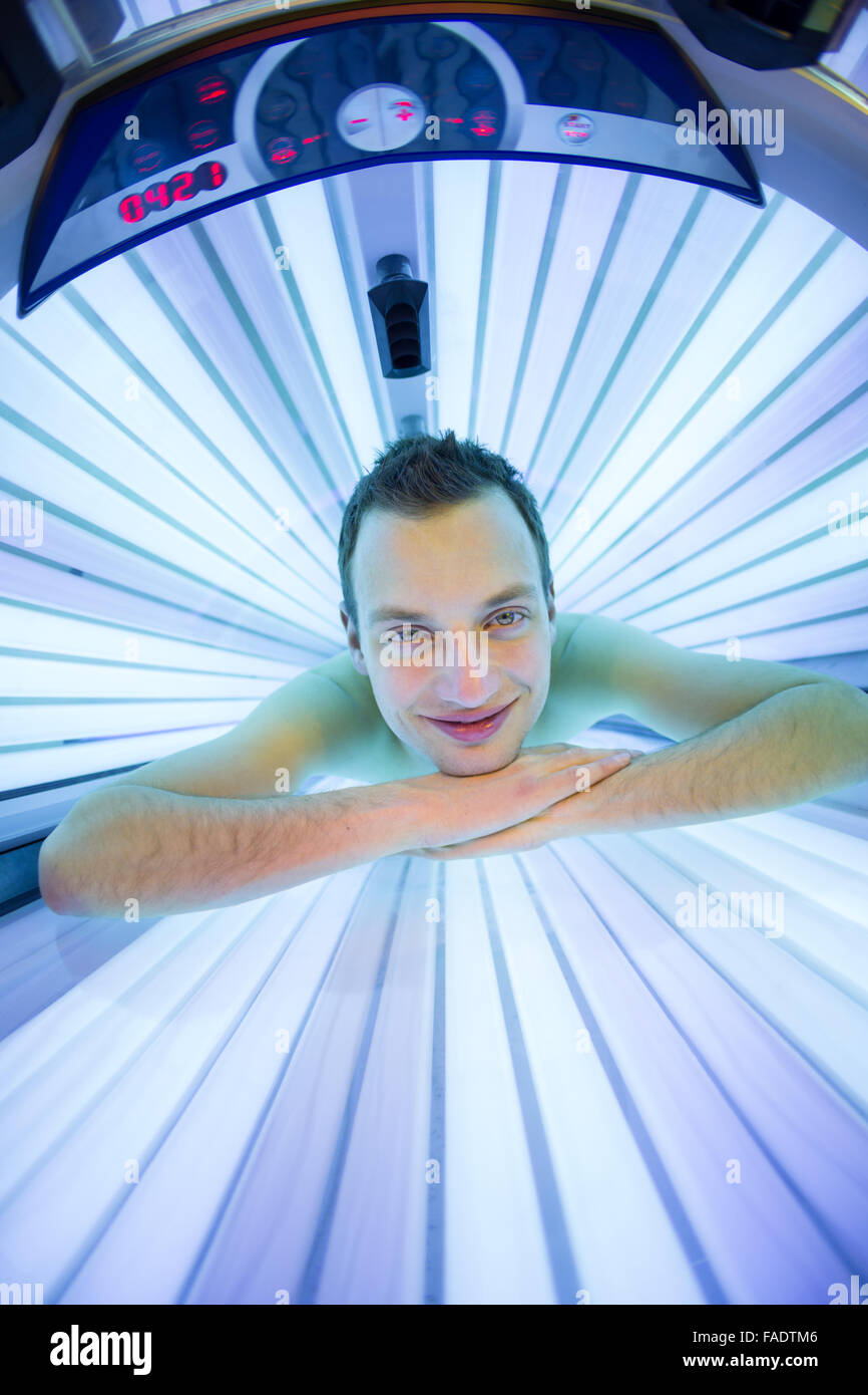 Handsome young man relaxing during a tanning session in a modern ...
