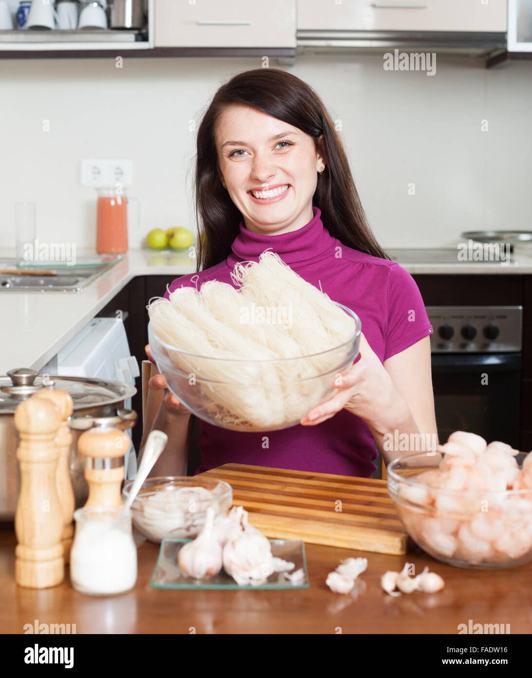 Happy girl cooking rice noodles with seafood in home kitchen Stock ...