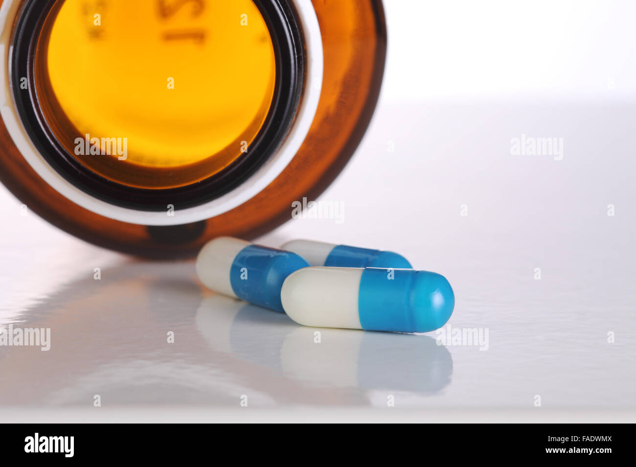 Capsules spilling from medicine bottle Stock Photo - Alamy