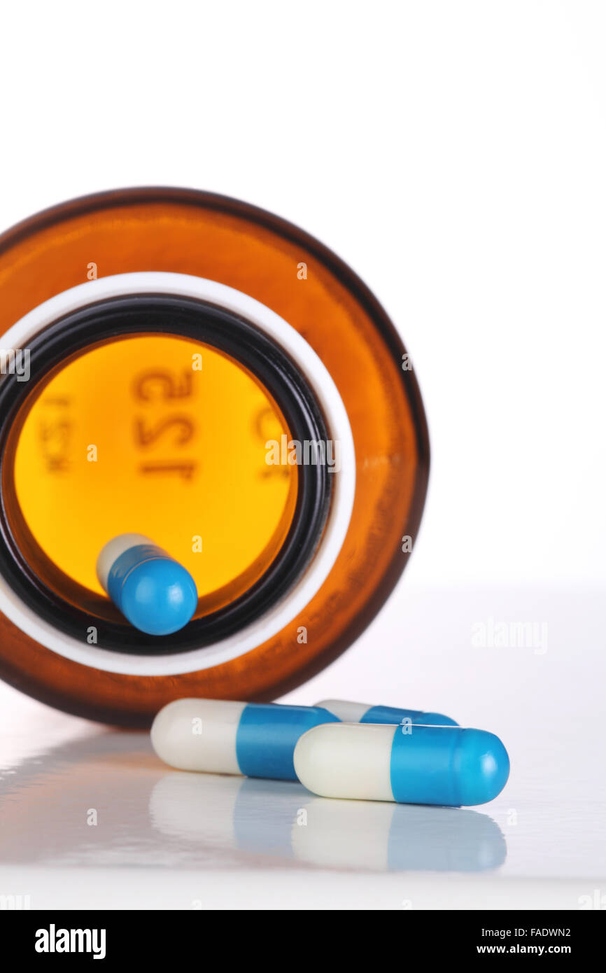 Capsules spilling from medicine bottle Stock Photo - Alamy