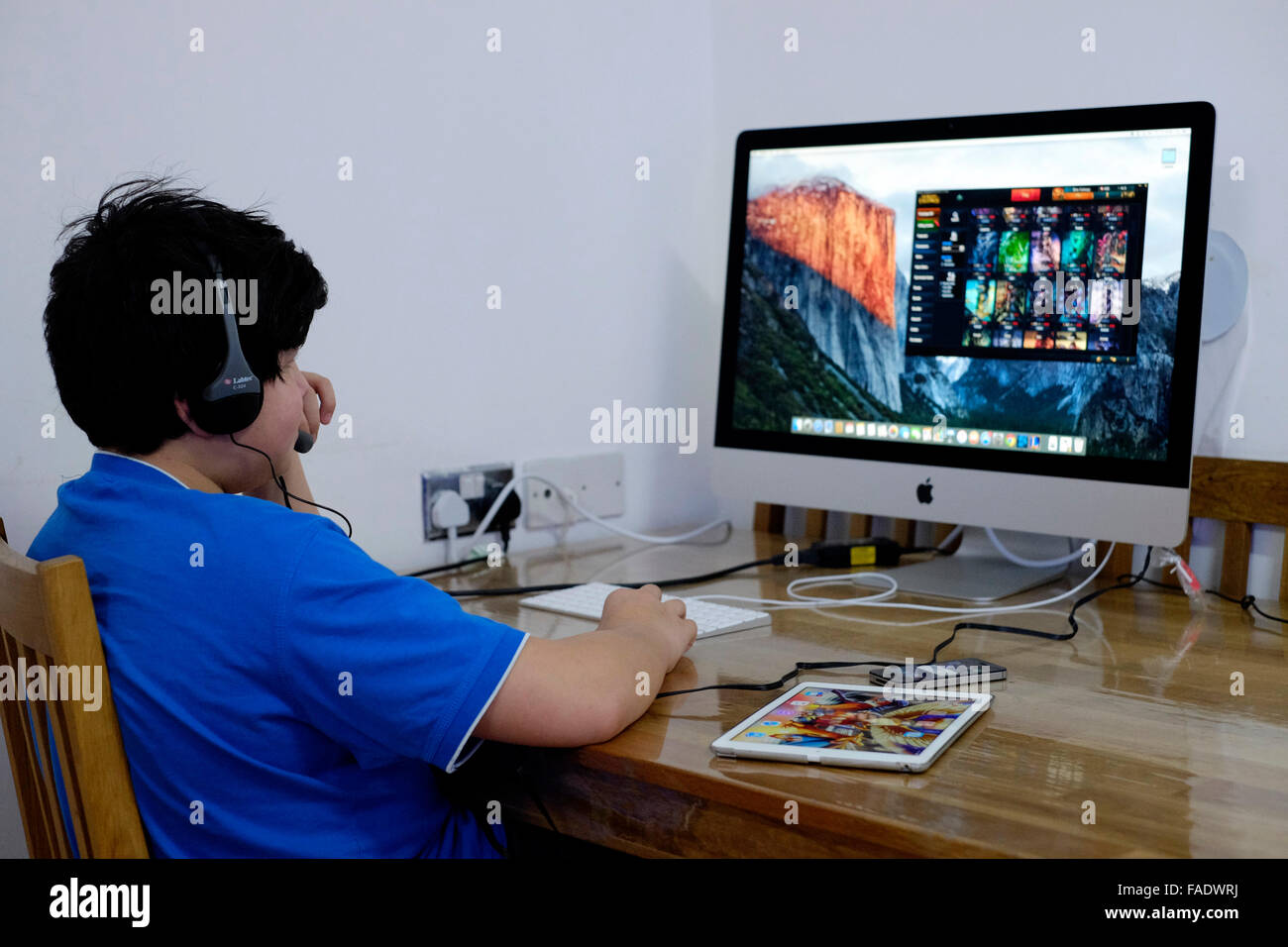 young boy sat playing games on computer surrounded by electronic ...