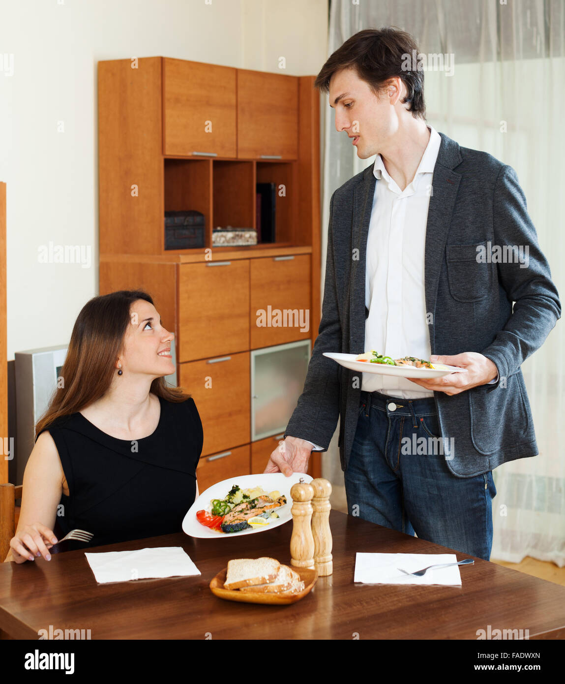 Smiling man serving dinner to beloved woman at table Stock Photo - Alamy