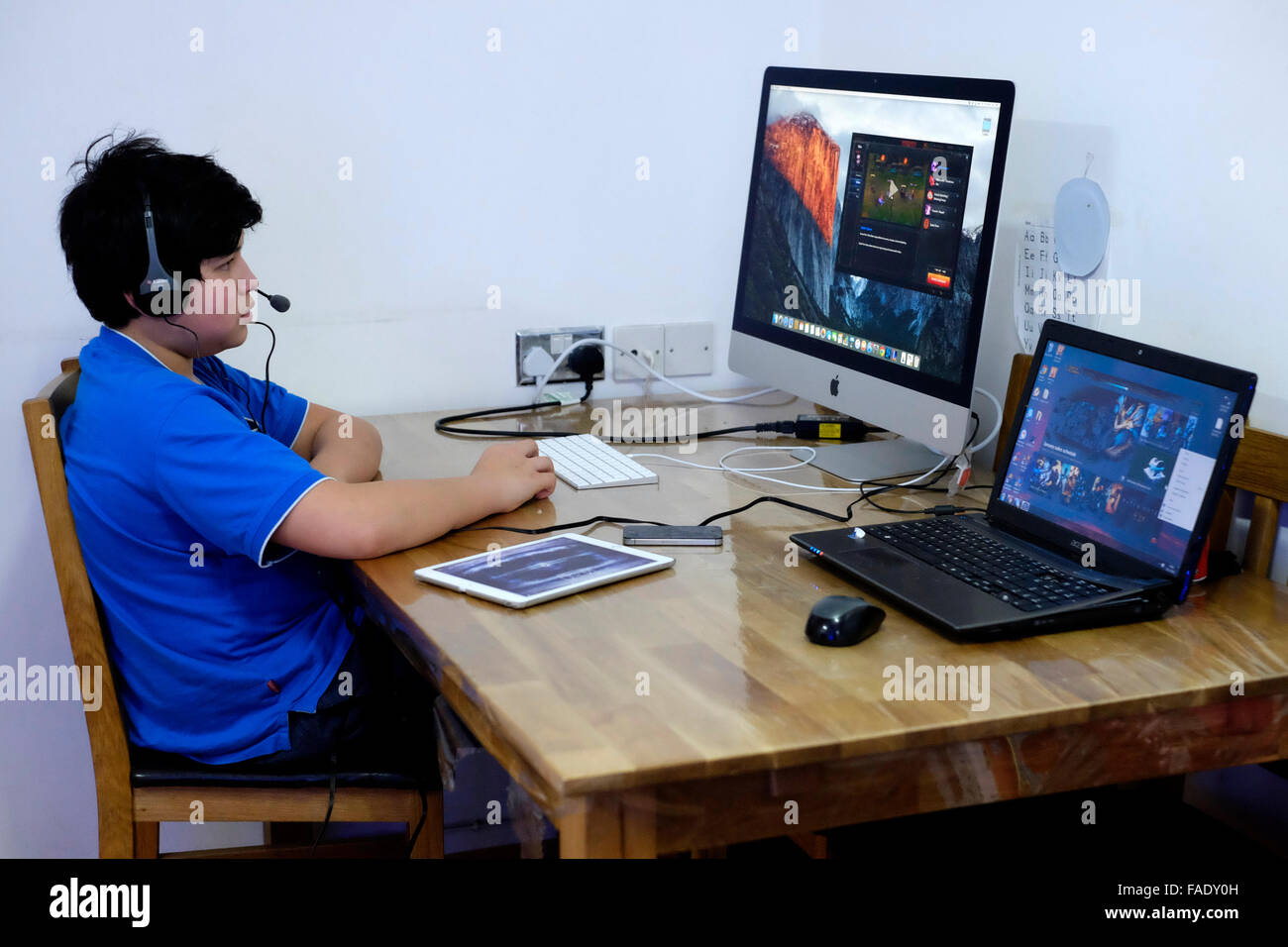 young boy sat playing games on computer surrounded by electronic ...