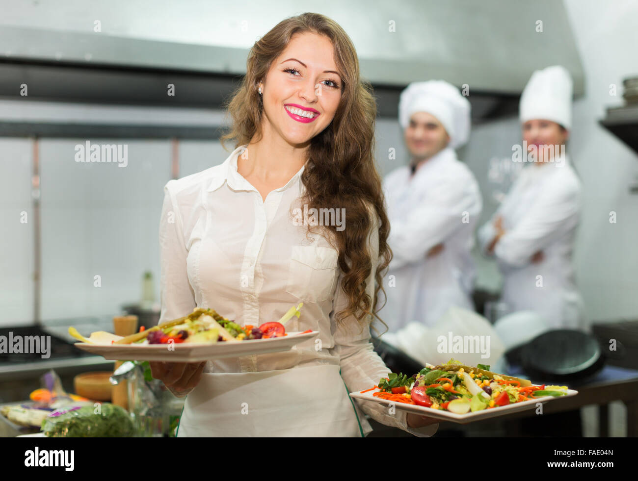 Team of chefs and young beautiful waiter at the restaurant kitchen ...