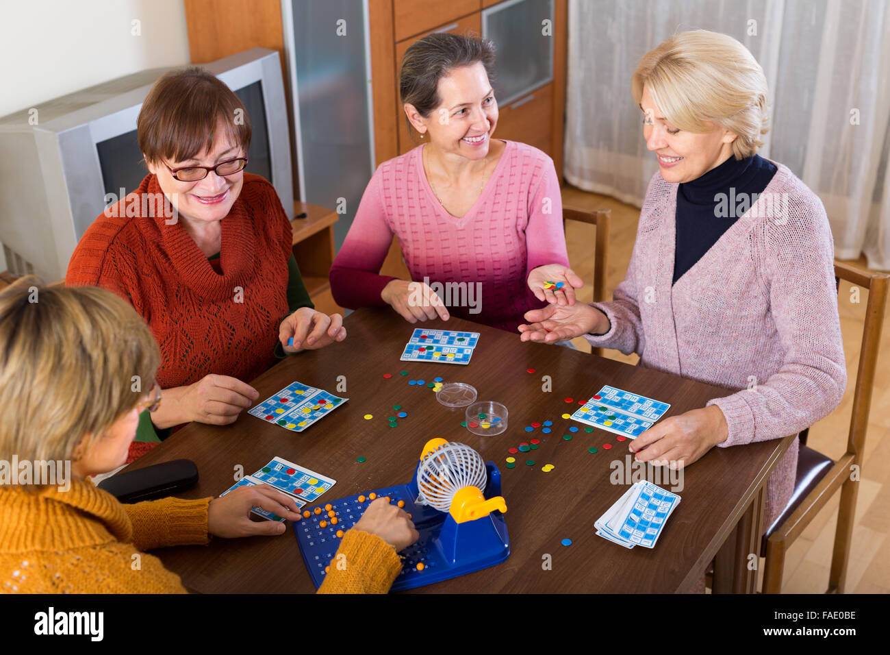 Positive senior female friends sitting at desk with bingo Stock Photo ...